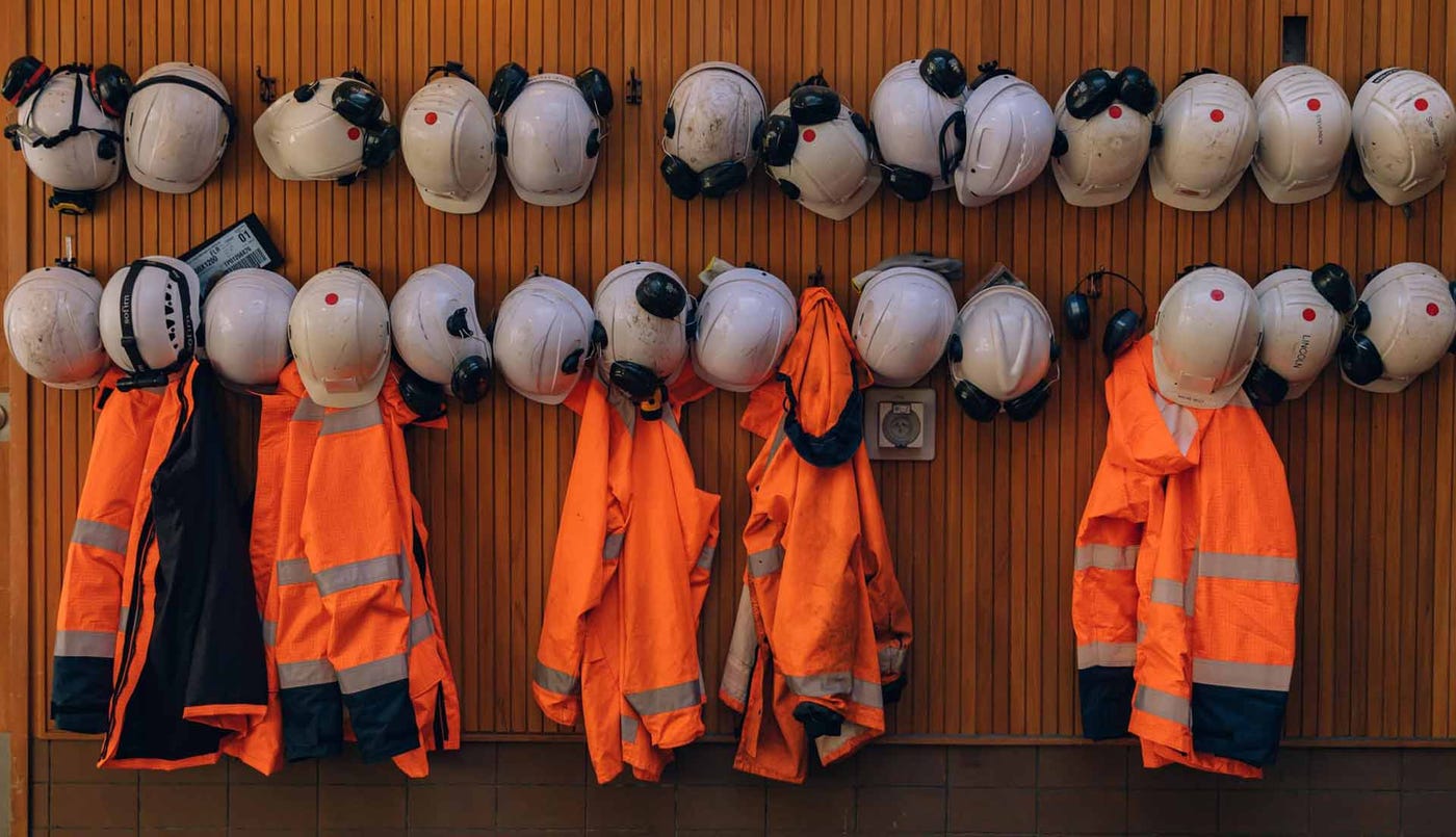 hard hats and high vis jackets hanging on wall